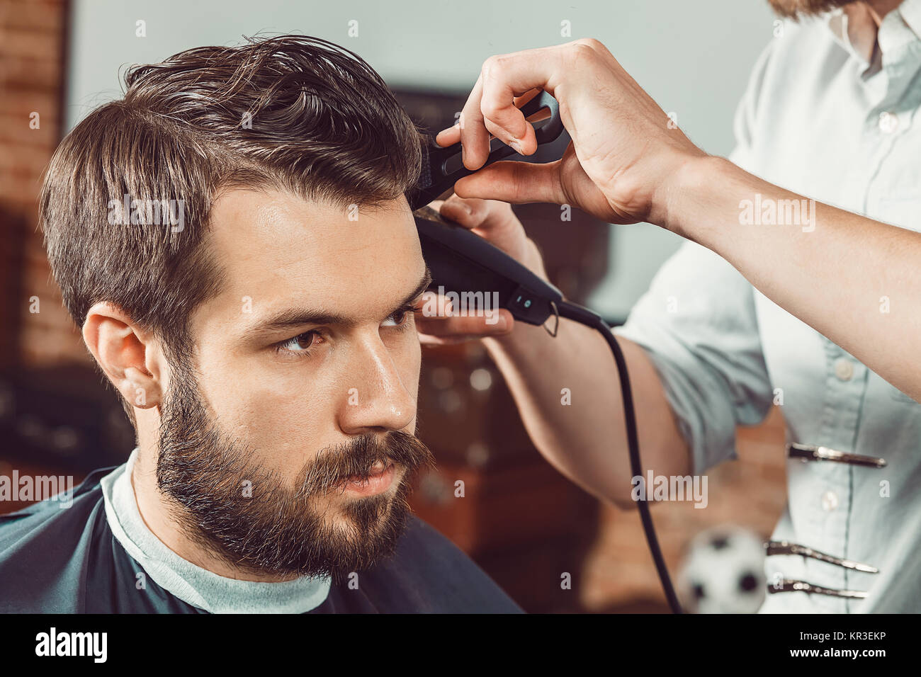 The hands of young barber making haircut attractive man in barbershop ...