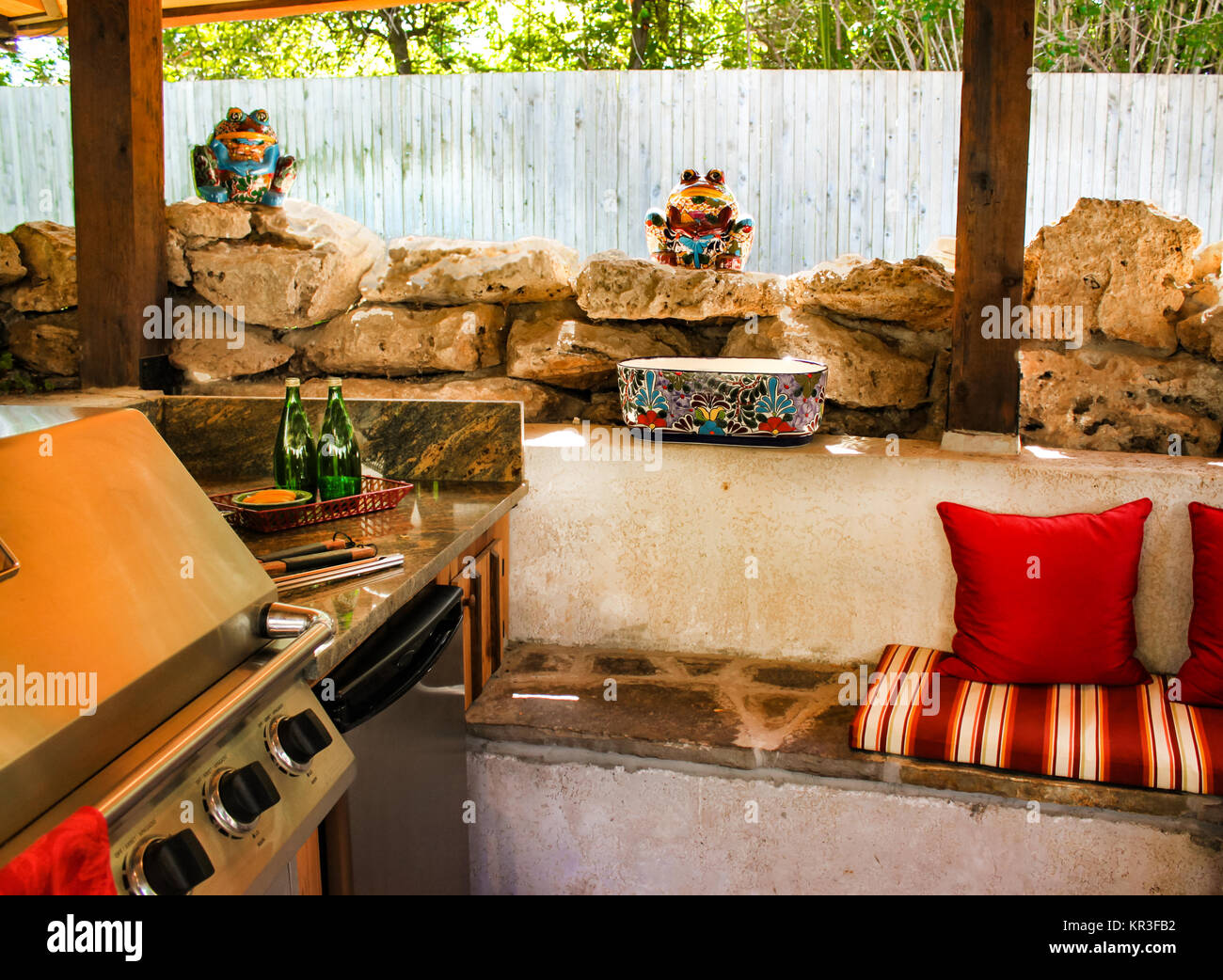 Outdoor barbeque area with stone benches and cushions and electric ...