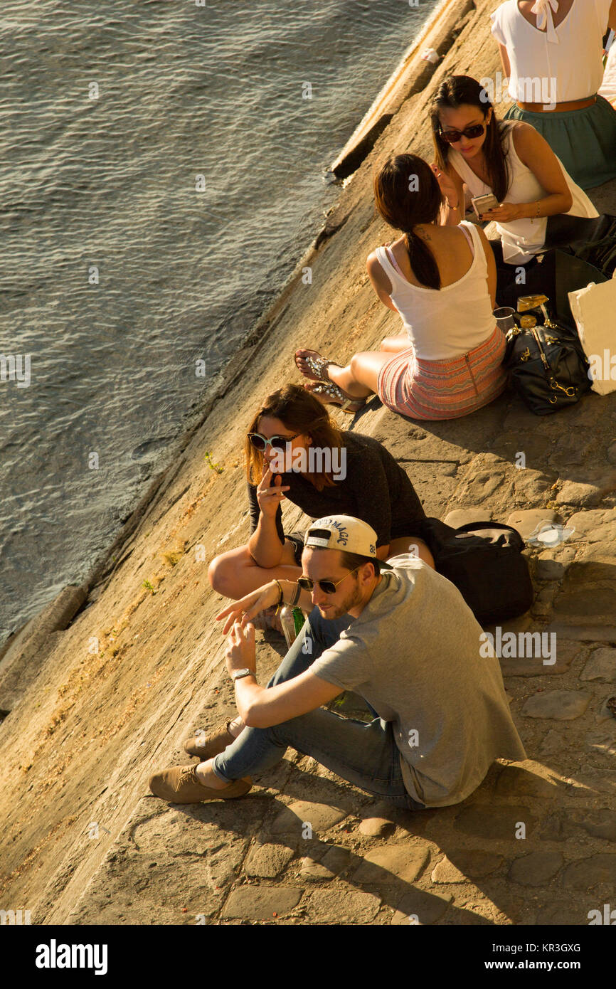 Many young people relaxing at summer afternoon in île Saint-Louis on the banks of river Seine in ...