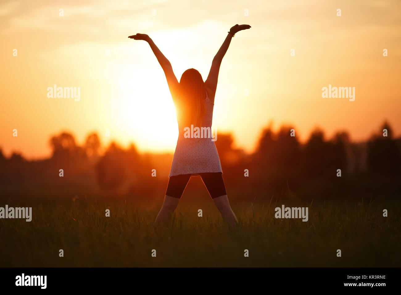 Girl with hands up on sunset background Stock Photo - Alamy