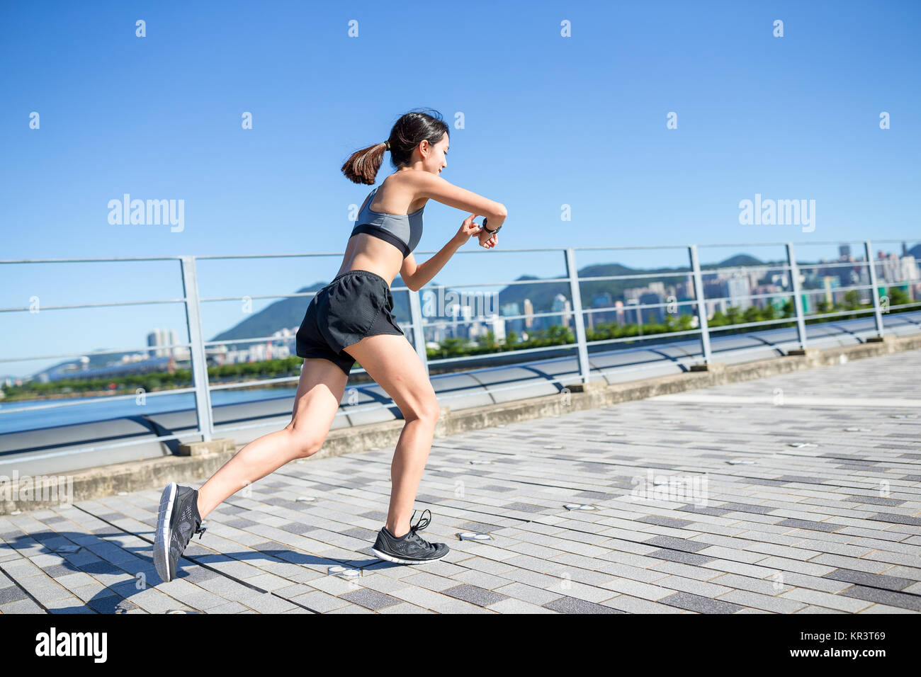 Woman running and using wearable watch at city Stock Photo - Alamy