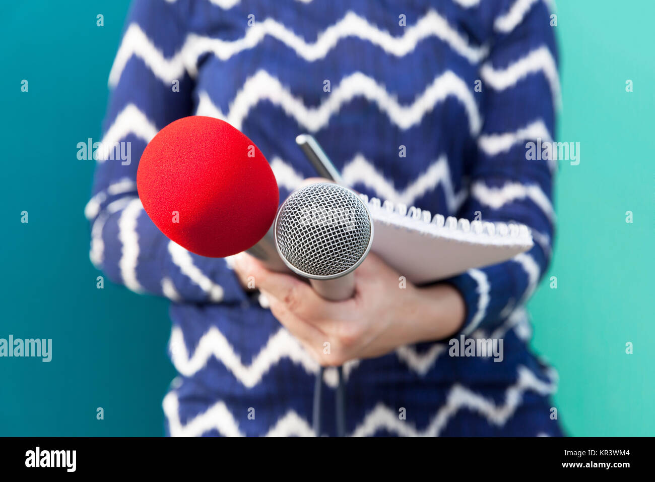 Female reporter at news conference, taking notes, holding microphones ...