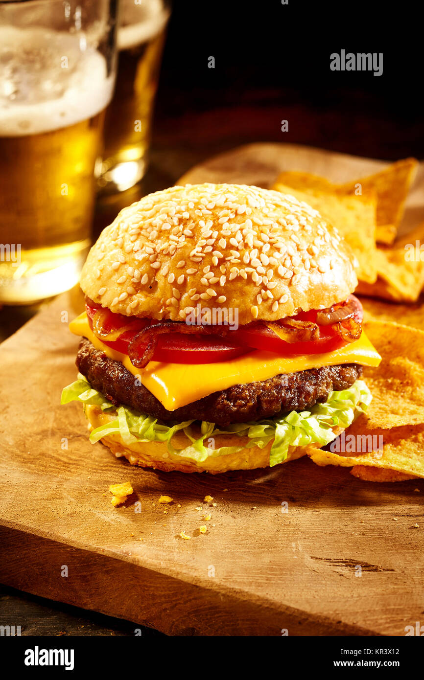 Single delicious well done burger topped with onions, tomatoes, cheddar ...