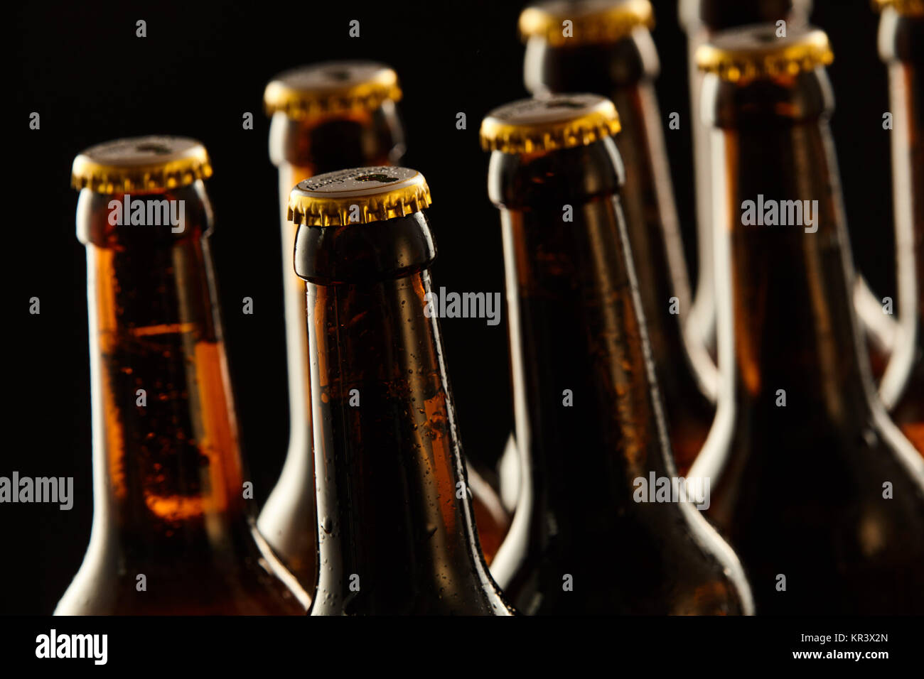 Rows of sealed beer bottles in a close up view of the necks and tops ...