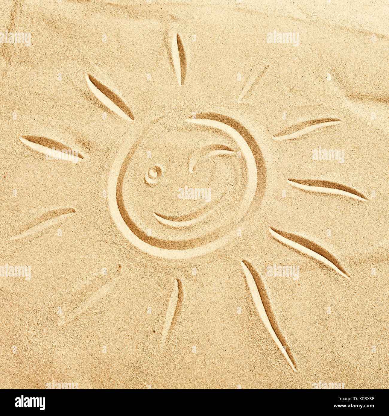 Smiling winking happy sun hand drawn on golden beach sand in a concept ...