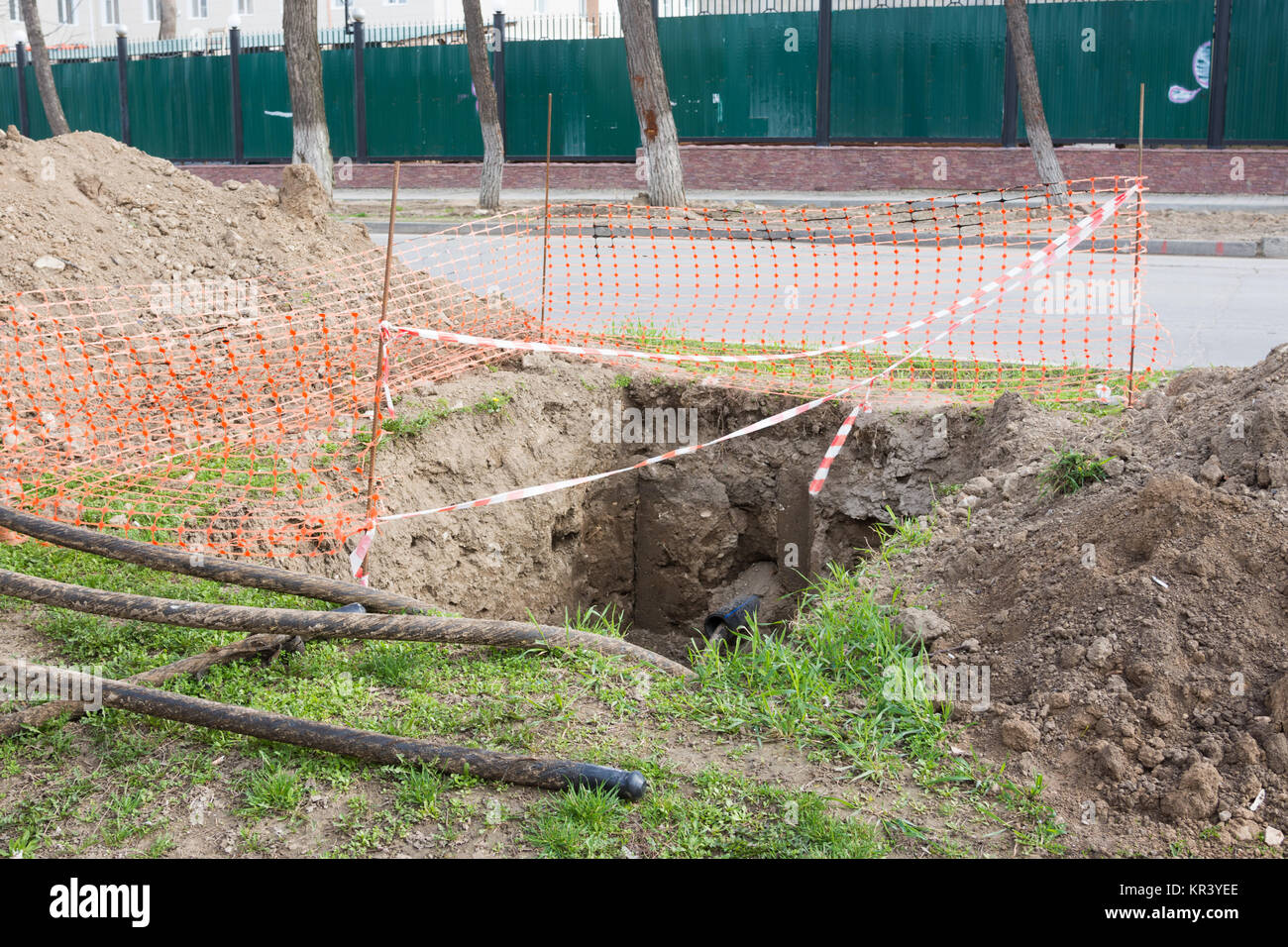 Dug pit fenced for replacing electric cables underground Stock Photo ...