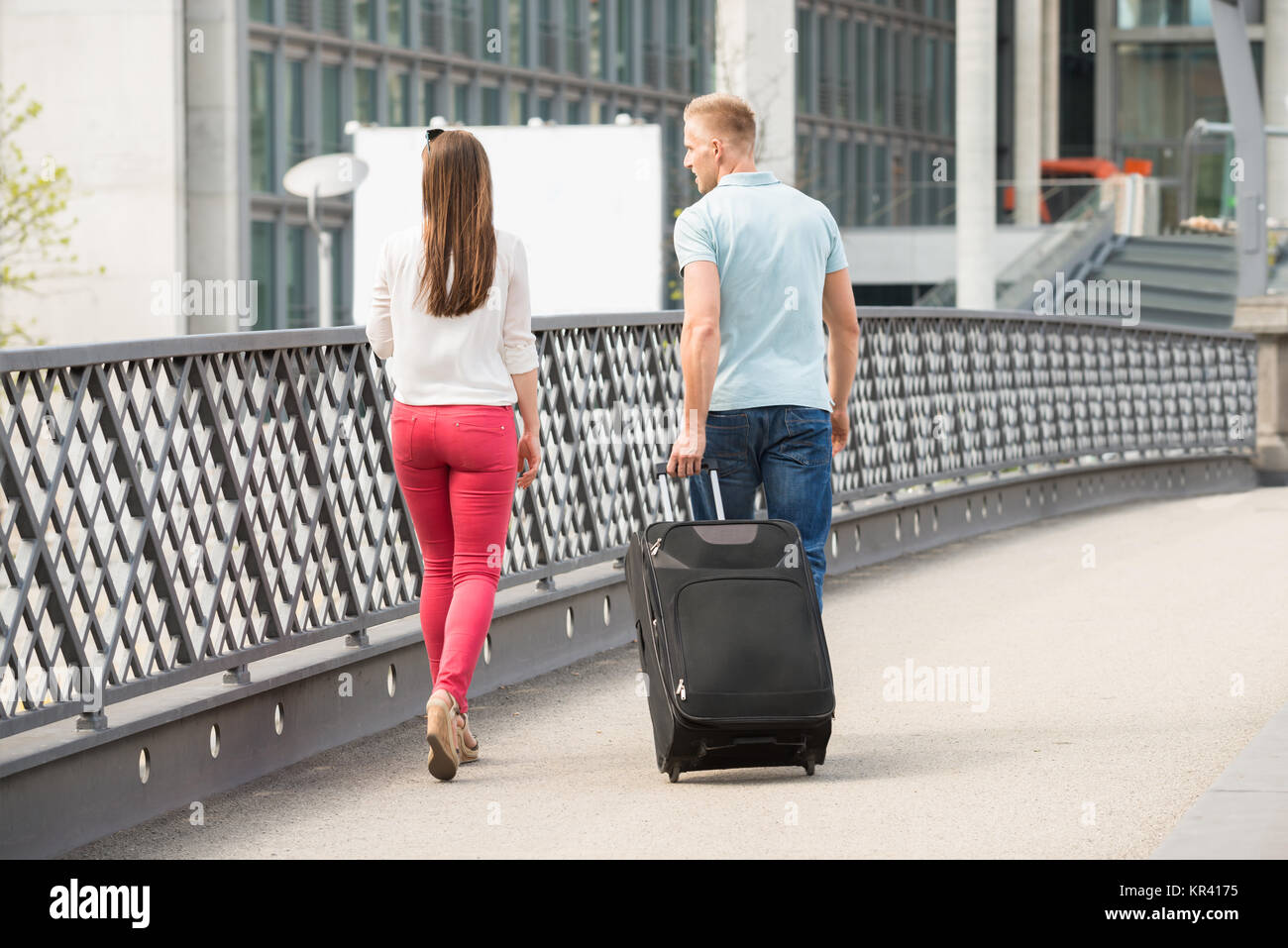 Couple Walking On Bridge With Luggage Stock Photo - Alamy