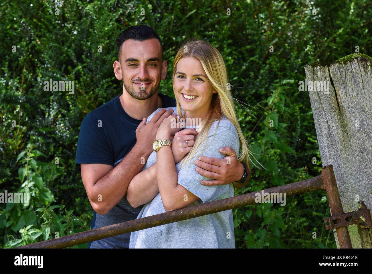 Man hugging blonde girlfriend by iron gate Stock Photo - Alamy