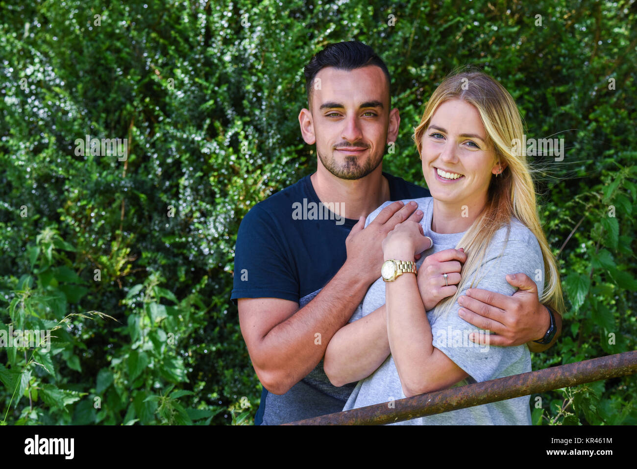 Man hugging smiling blonde girlfriend behind gate Stock Photo - Alamy