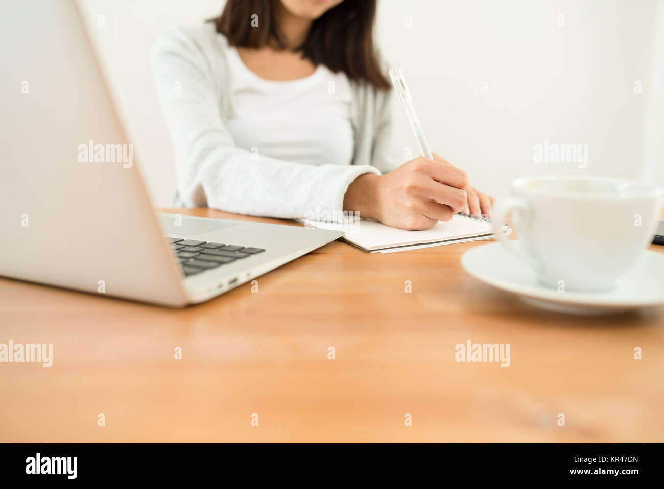 Woman writing on the note book on her desk Stock Photo - Alamy