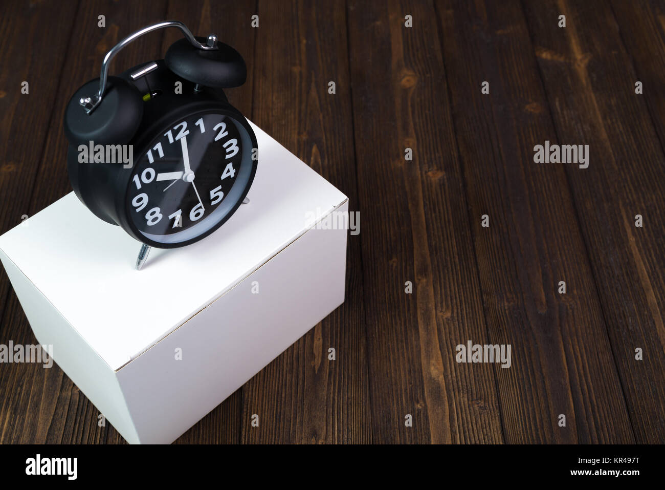 Vintage black alarm clock with white packaging gift box on dark wood ...