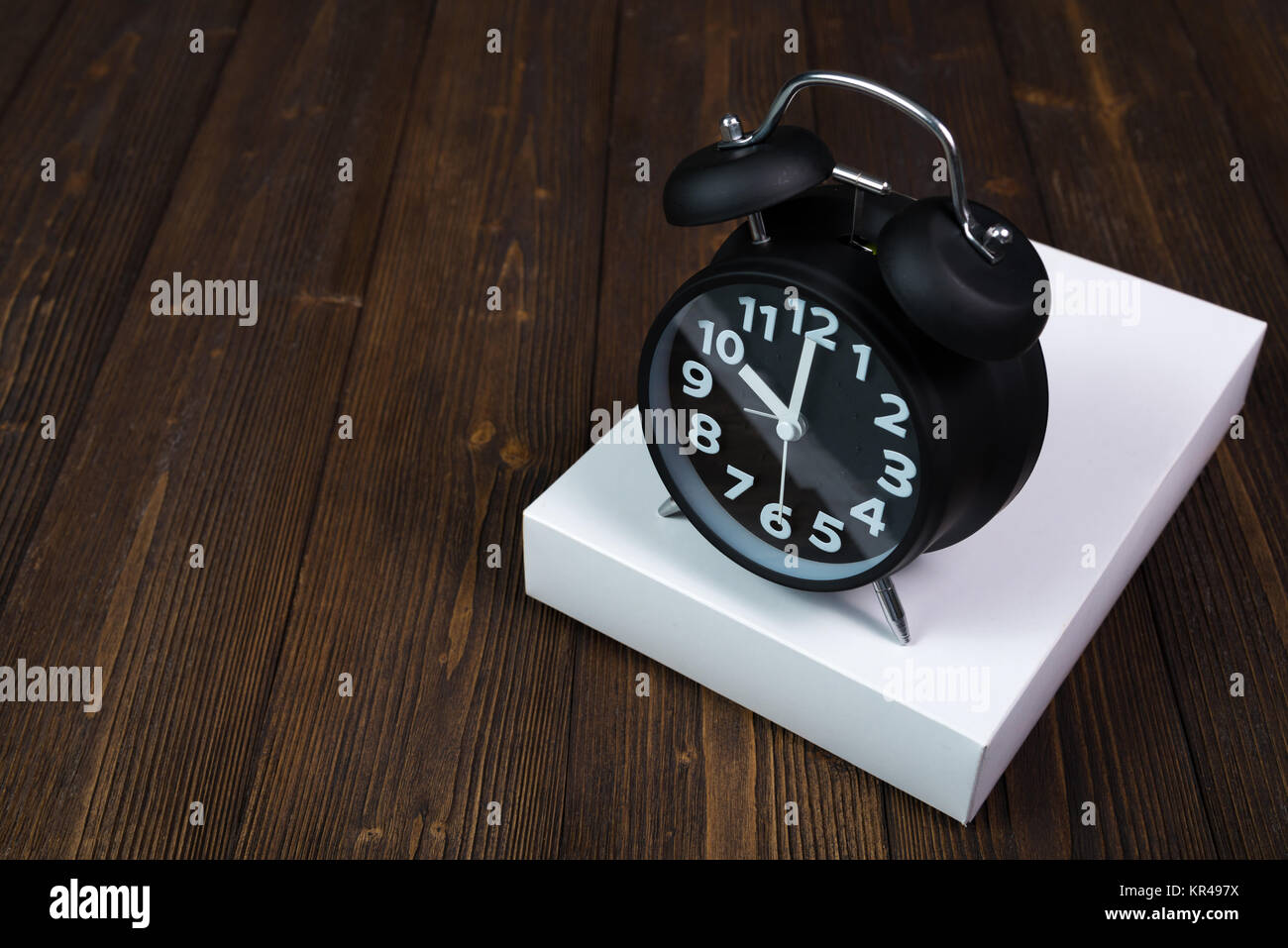 Vintage black alarm clock with white packaging gift box on dark wood ...