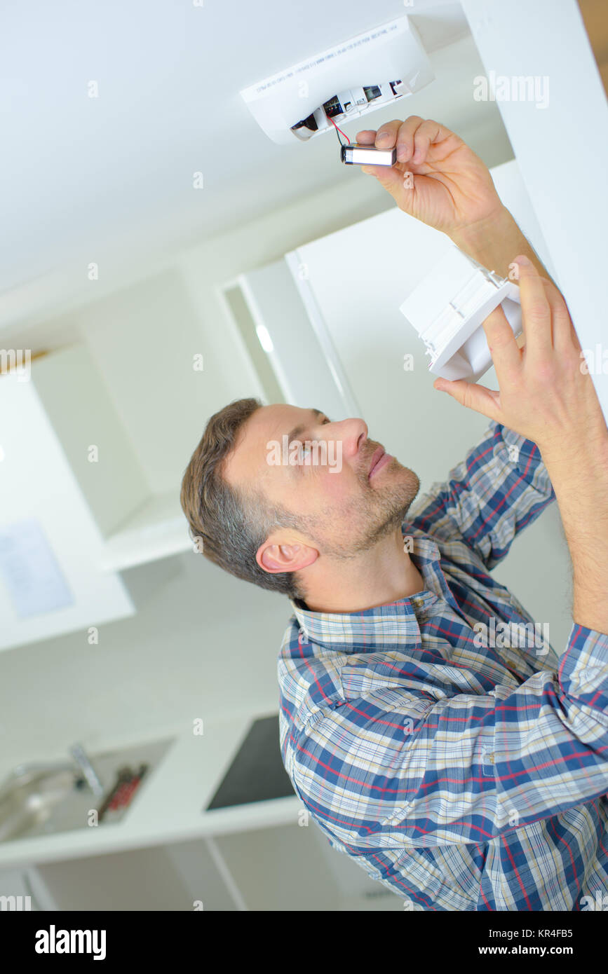 Safety conscious man fitting a fire smoke alarm Stock Photo - Alamy