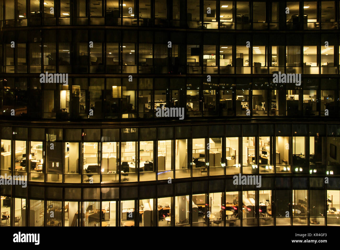 yellow light windows of an office building at night in Boston late ...