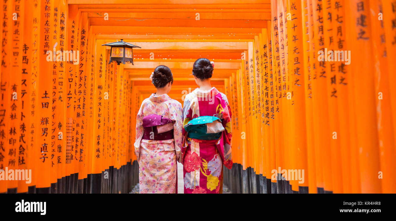 Two geishas among red wooden Tori Gate at Fushimi Inari Shrine in Kyoto ...