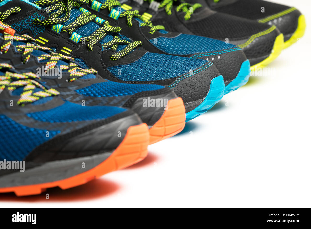 Three pairs of colourful exercise trainers / running shoes lined up in ...