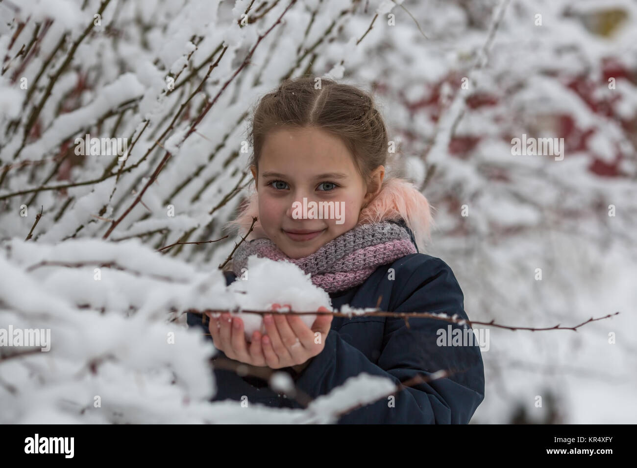 Cute little girl holds snow in hands Stock Photo - Alamy