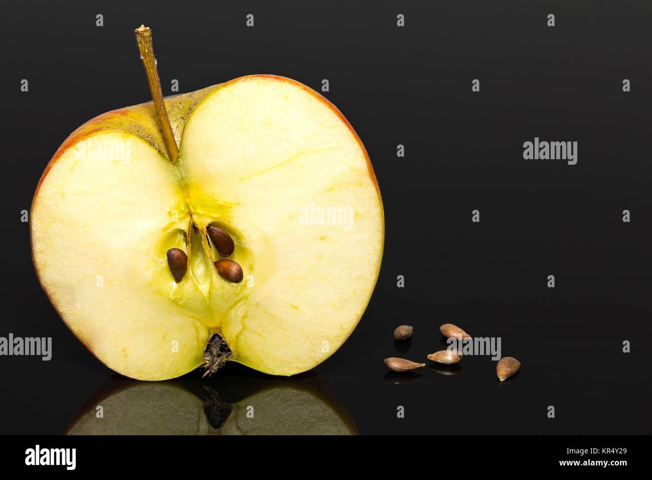 half of apple with some pips on dark background Stock Photo - Alamy