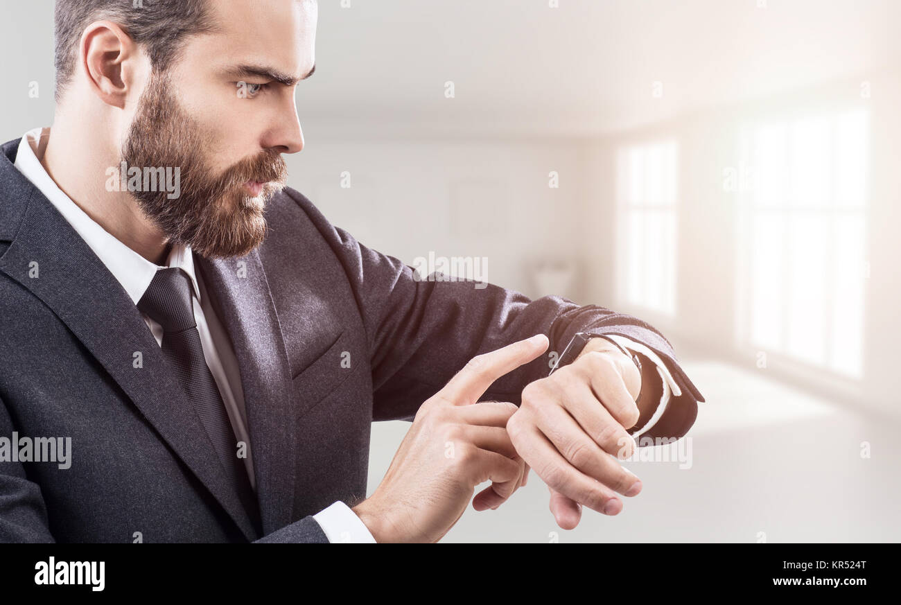 Handsome young businessman using smartwatch Stock Photo - Alamy