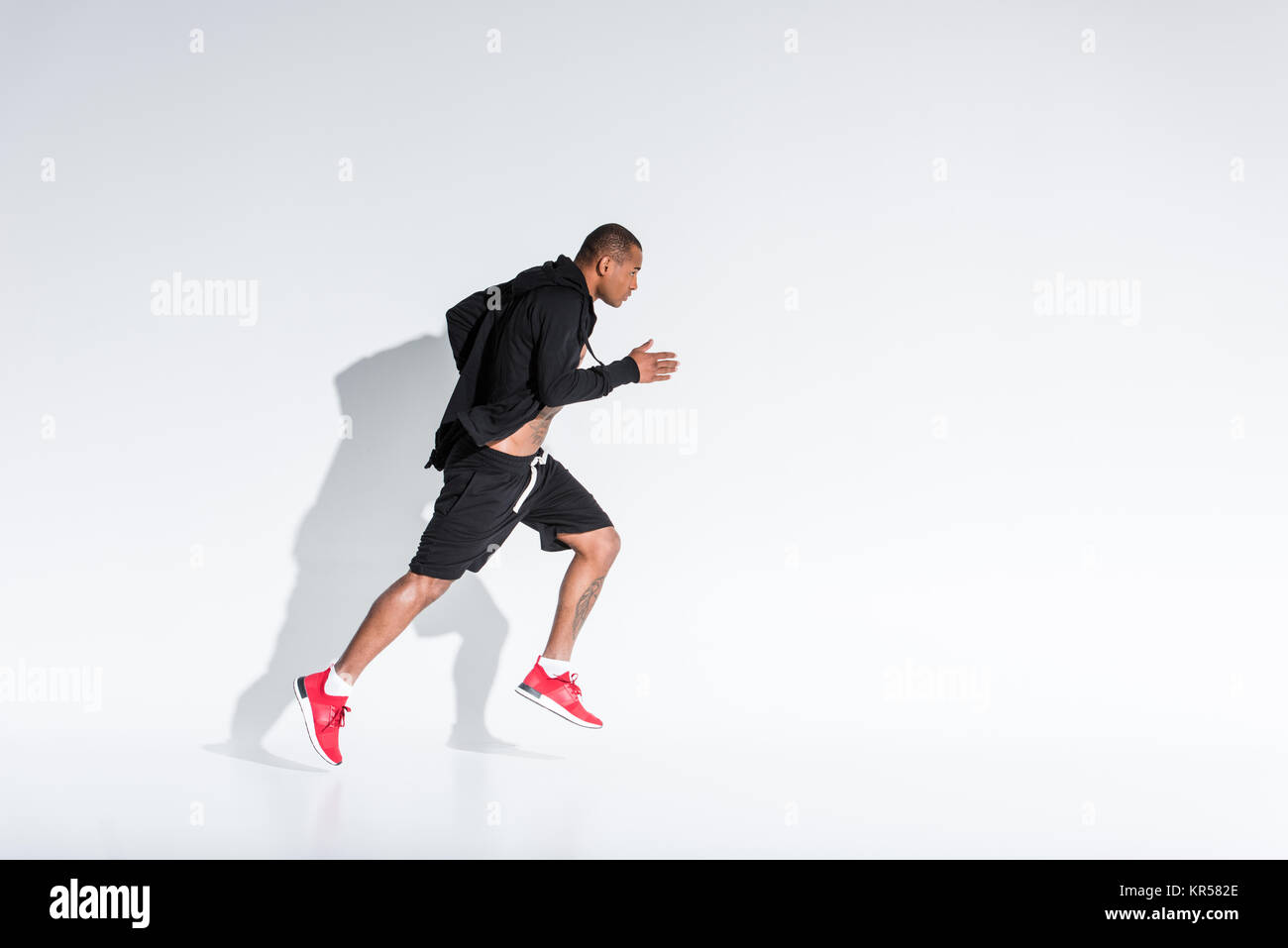 side view of young african american sportsman in sportswear running on ...