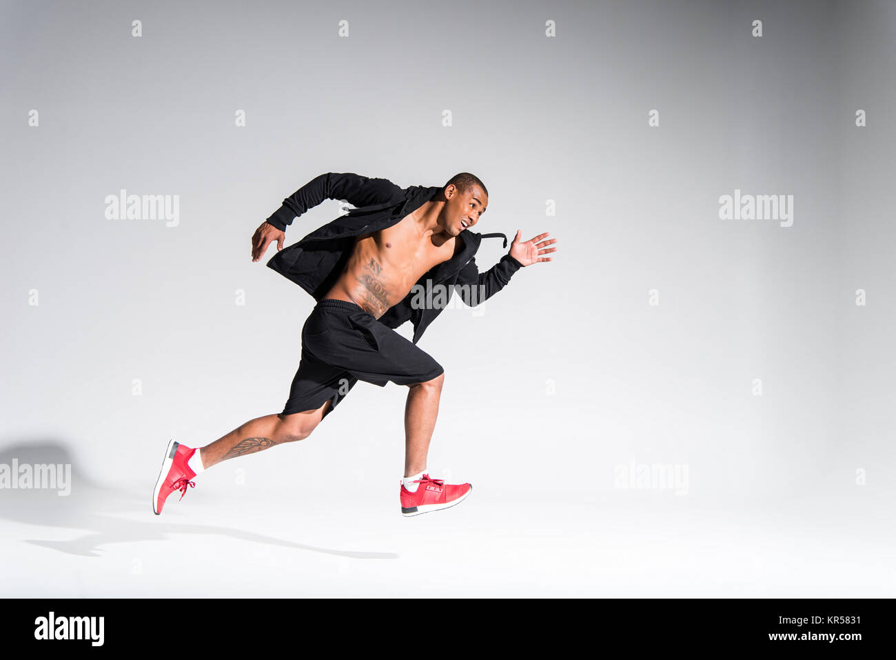 young african american sportsman running on grey Stock Photo - Alamy