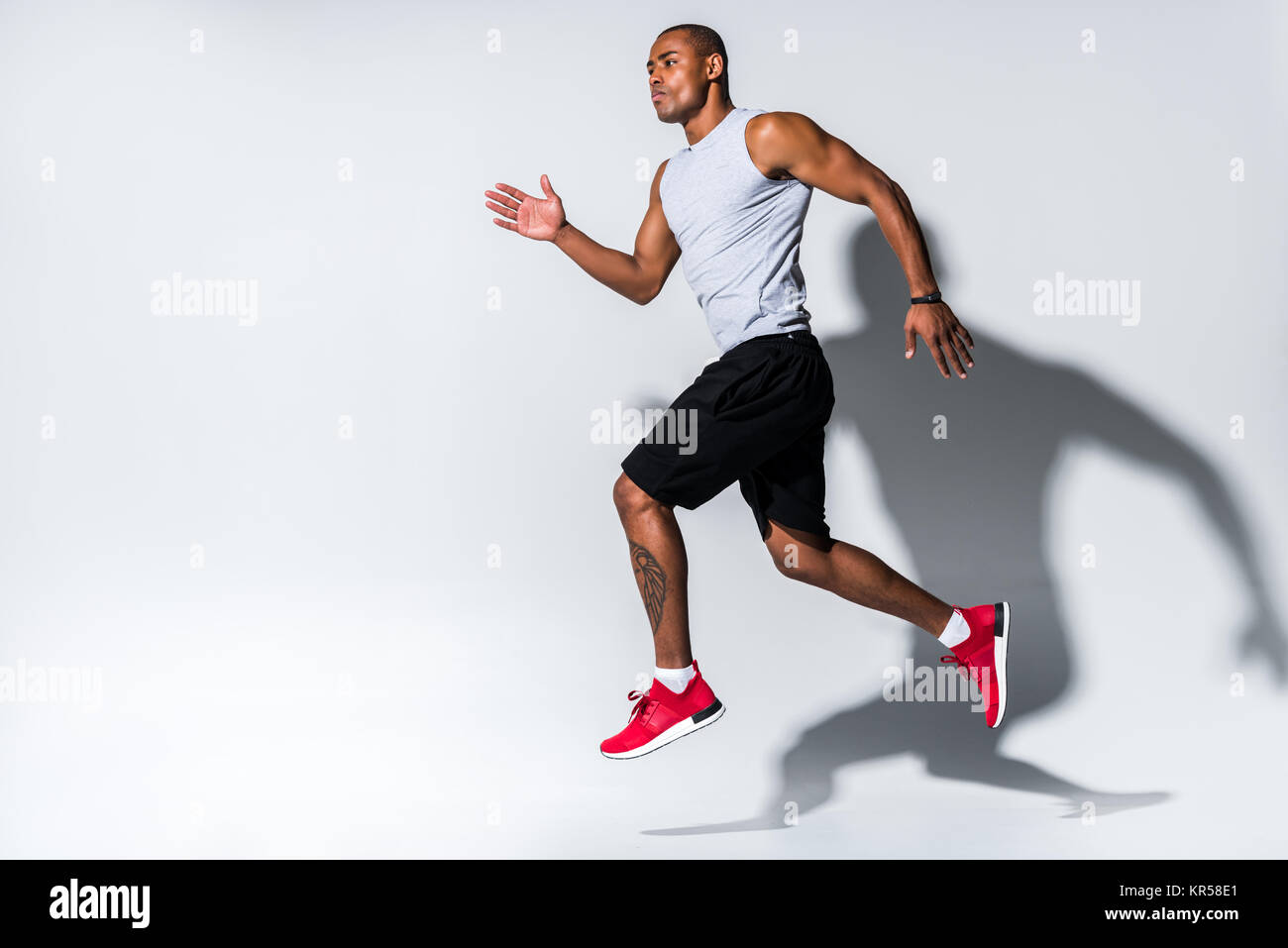 athletic young african american sportsman running on grey Stock Photo ...