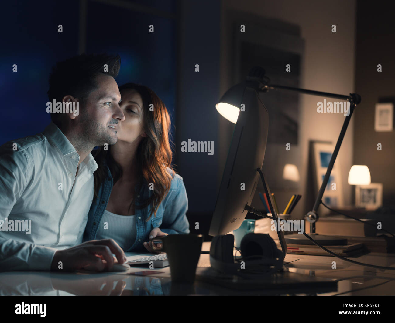 Happy romantic couple at home connecting with their computer, the woman ...