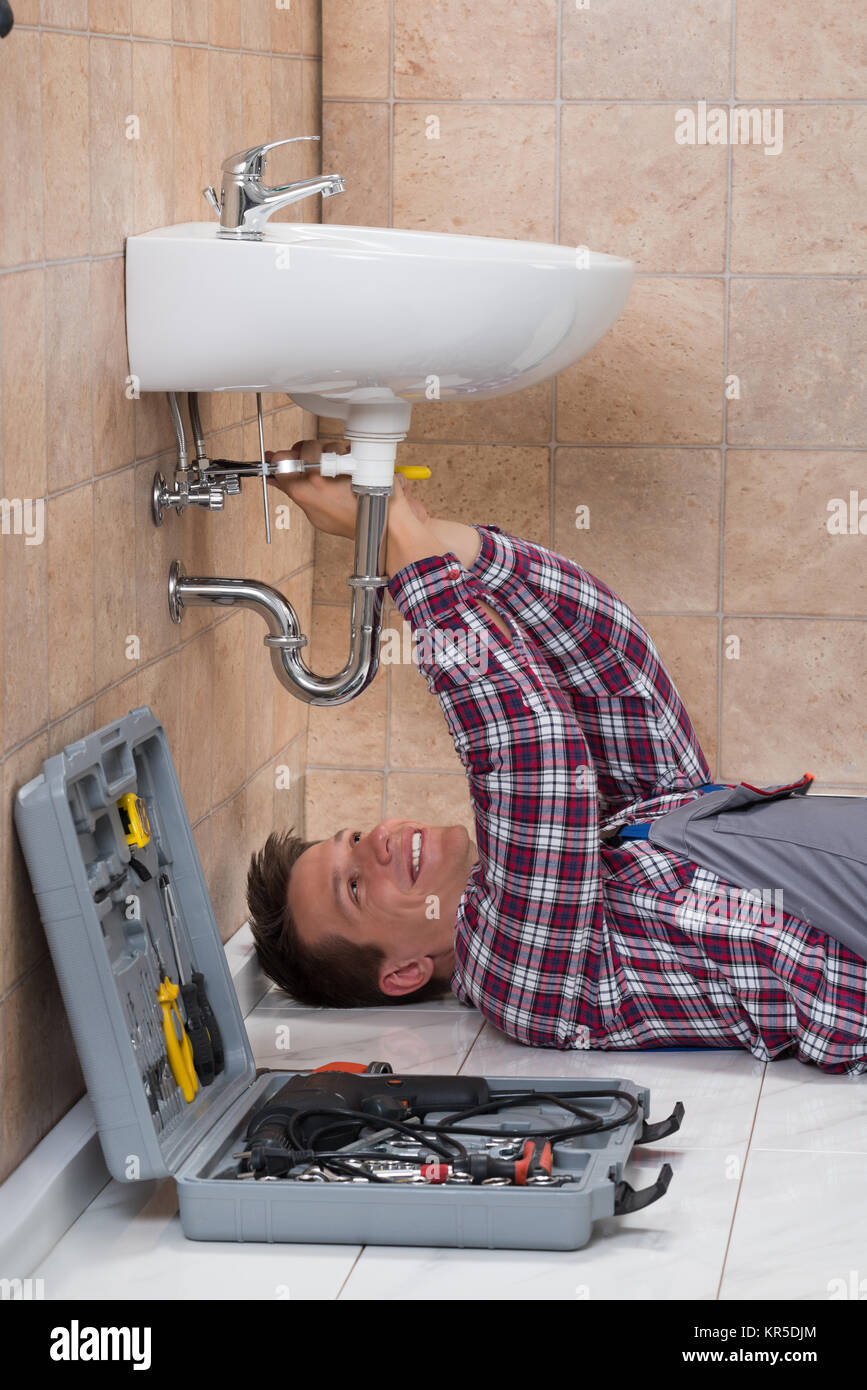 Plumber Lying On Floor Fixing Sink Stock Photo - Alamy