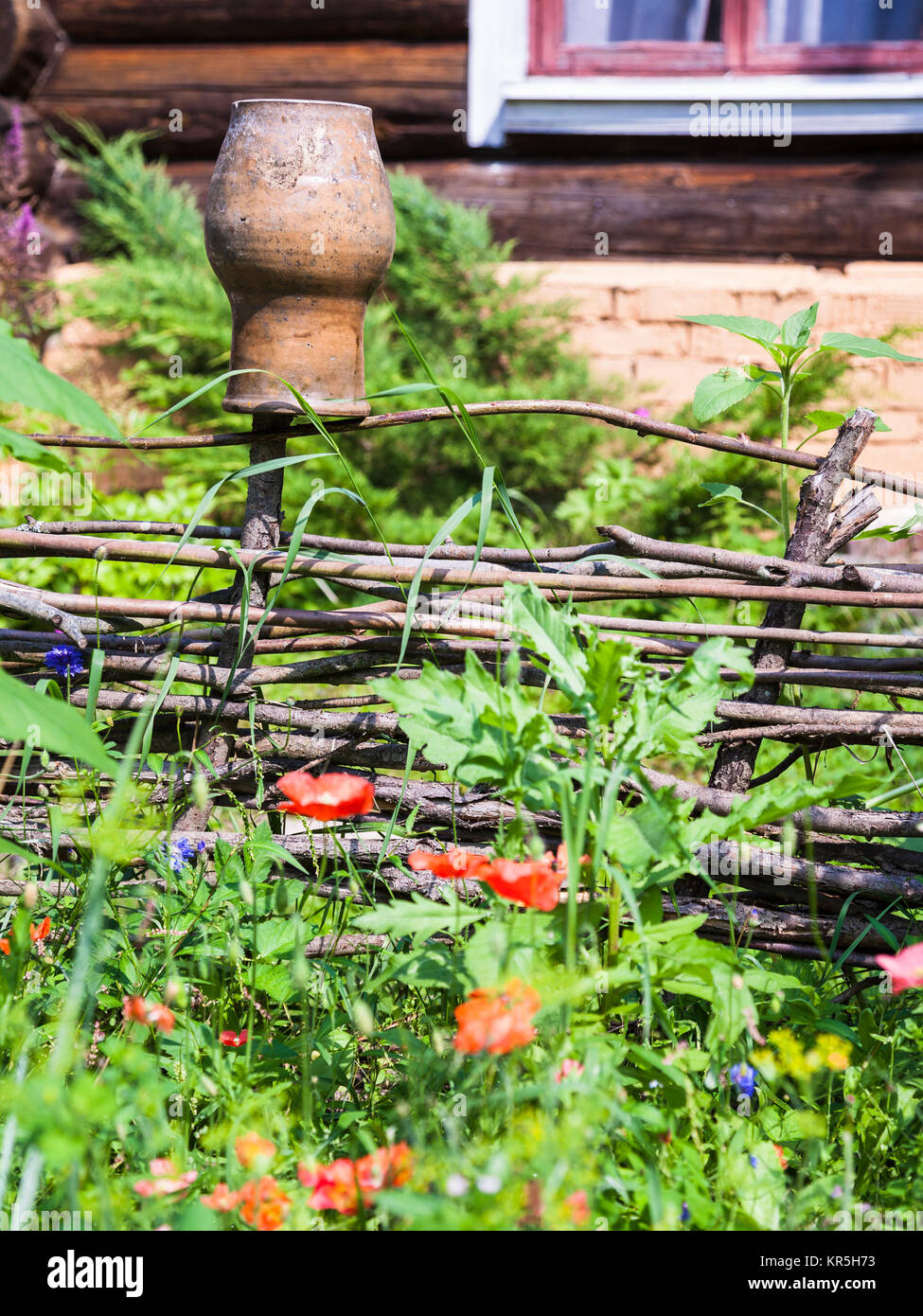 wattle hurdle with clay pot and old cottage Stock Photo - Alamy