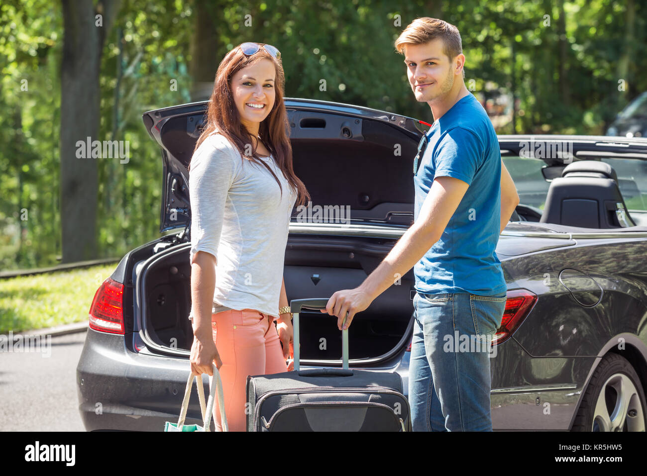 Smiling Couple Putting Luggage In A Car Trunk Stock Photo - Alamy