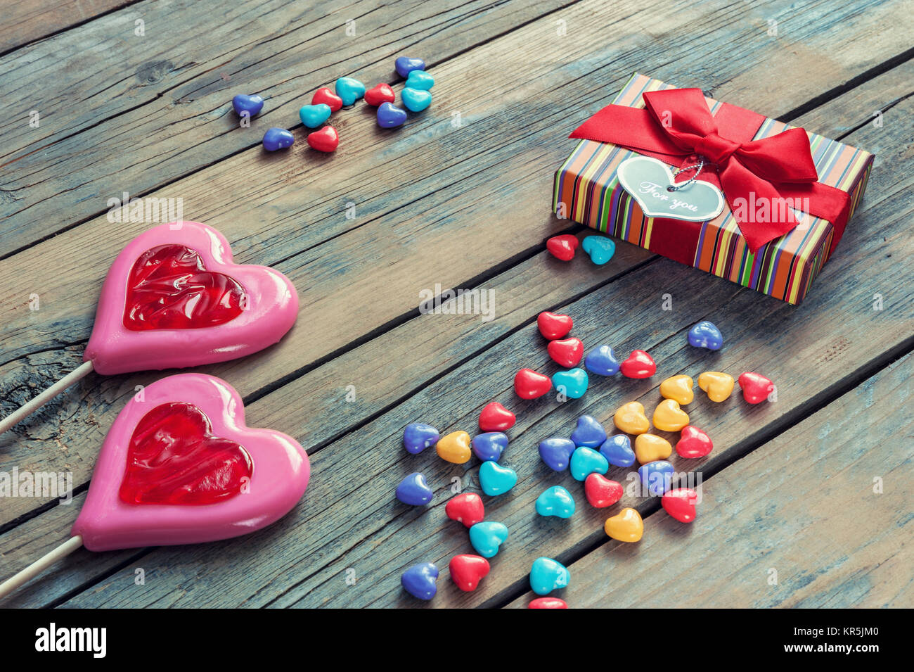 Two hearts and little colorful candy hearts. Wooden background ...