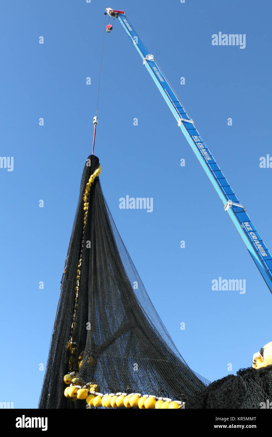 Hoist lift up big industrial black fishing net over blue sky background ...