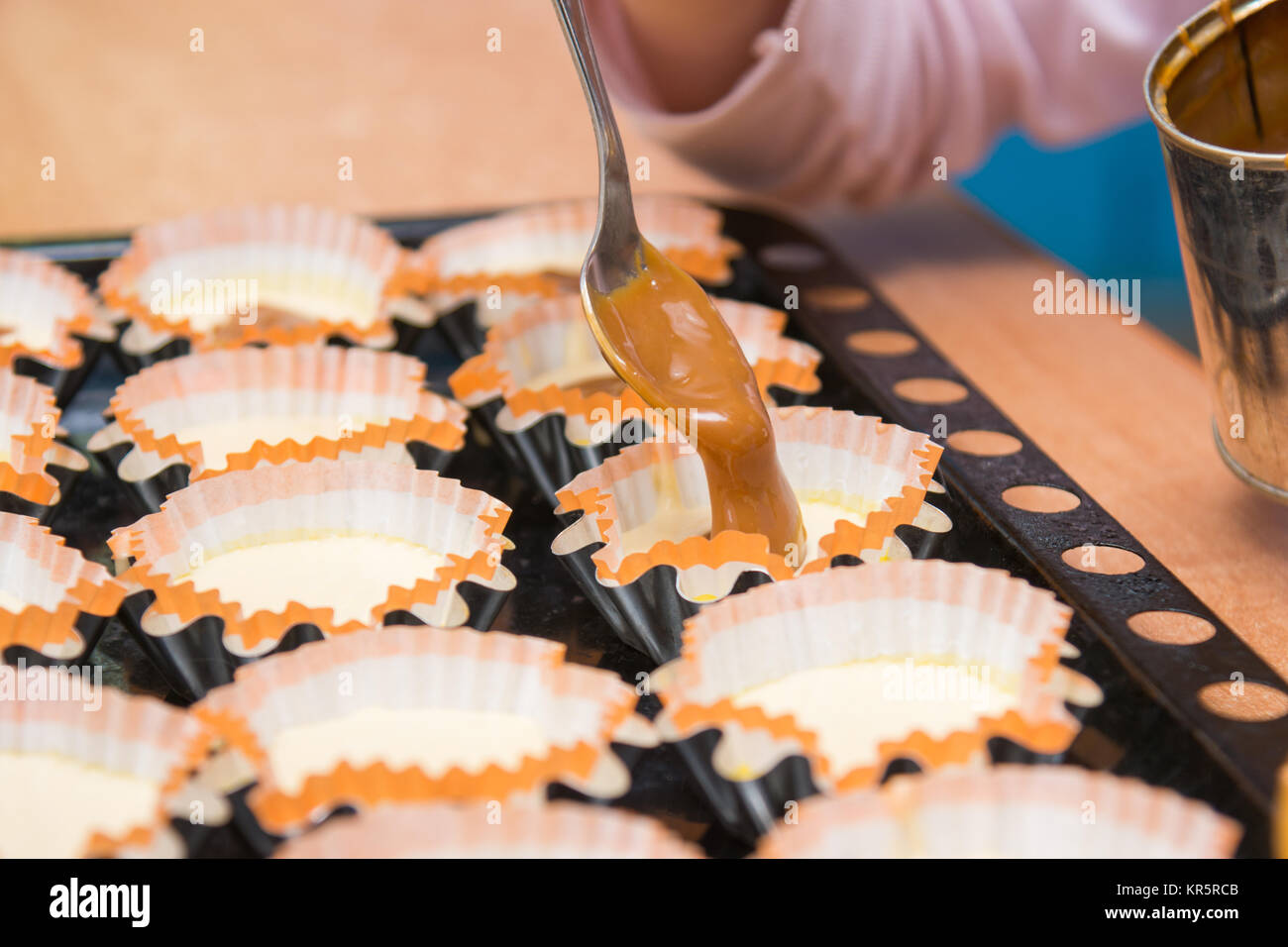 Boiled condensed milk is added as a filling into molds of muffins Stock ...