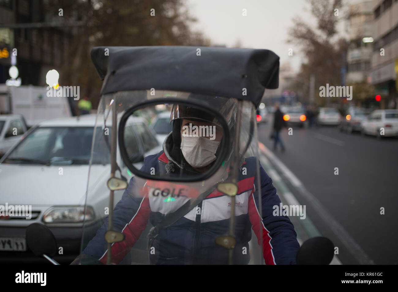 Tehran, Iran. 18th Dec, 2017. A man wearing a face mask drives a ...