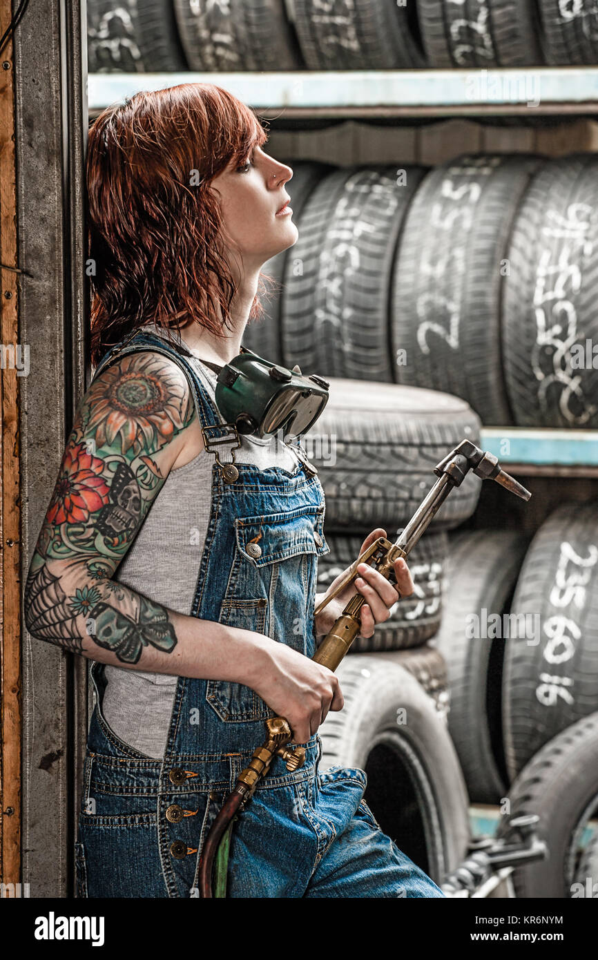 Photo of a beautiful redhead female mechanic with tattoos holding a ...