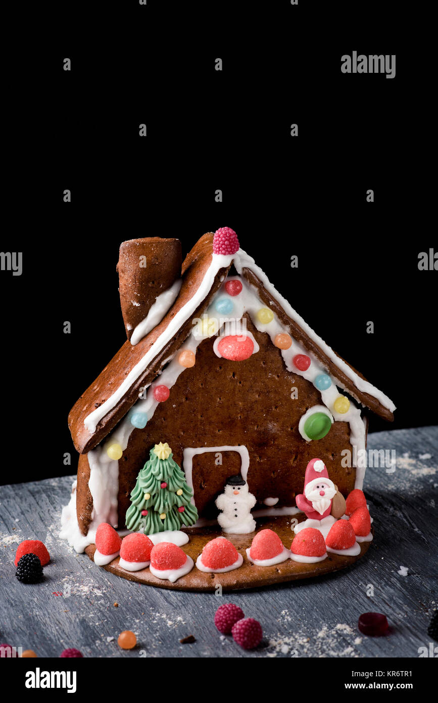 a messy homemade gingerbread house on a rustic wooden table, againt a ...