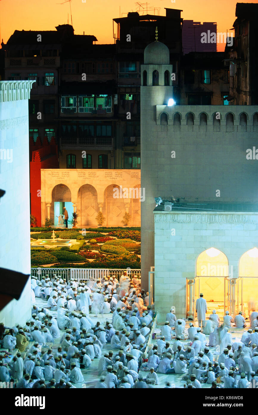 Large group of men gathered around mosque at dusk Stock Photo - Alamy