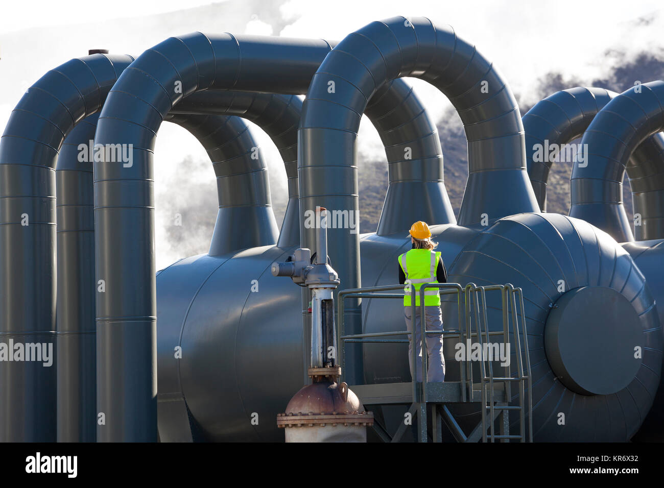 Rear view of woman engineer standing on a platform at a Geothermal ...