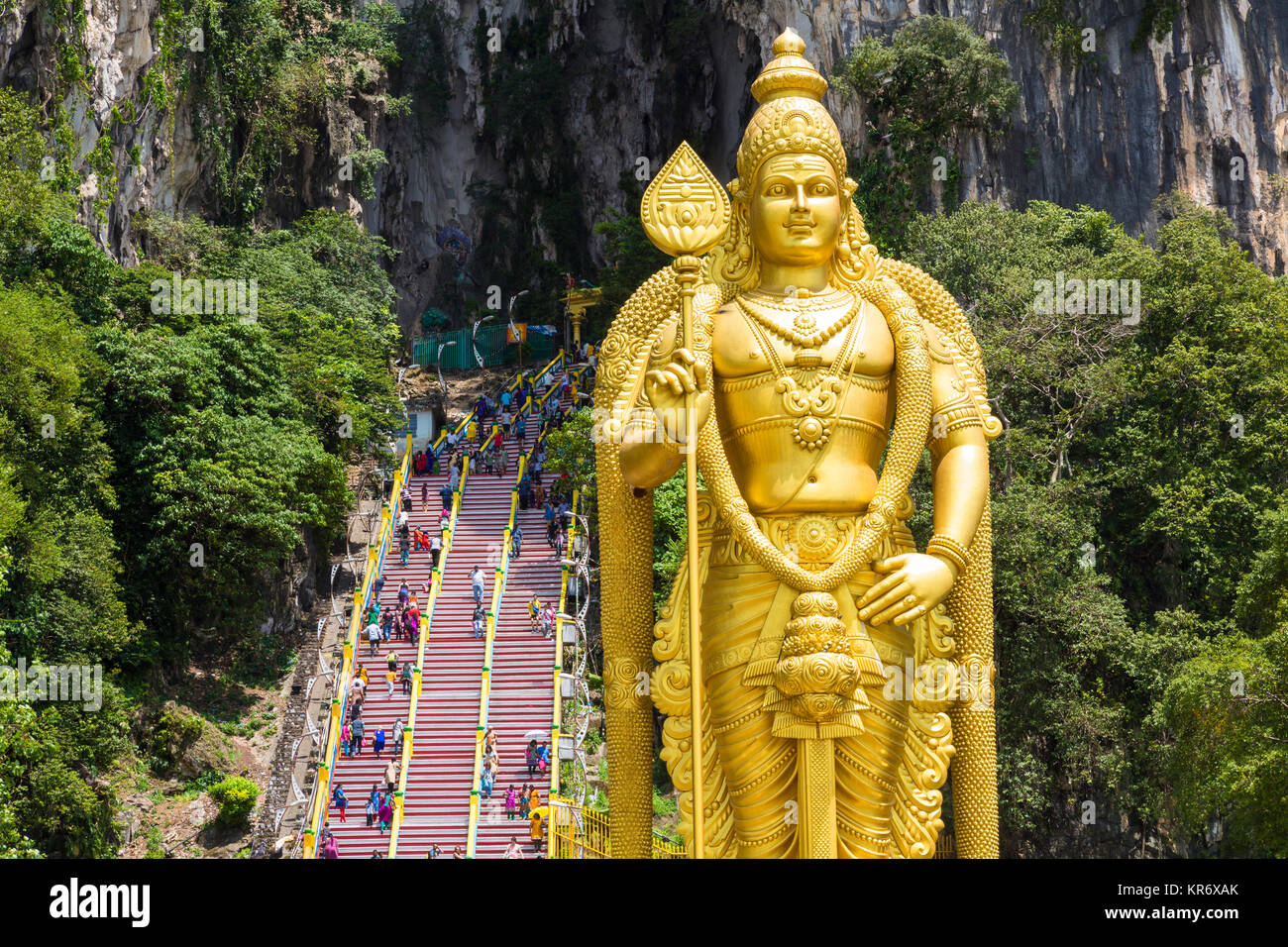 Colossal golden statue of Hindu deity, with stairway into cave in the ...