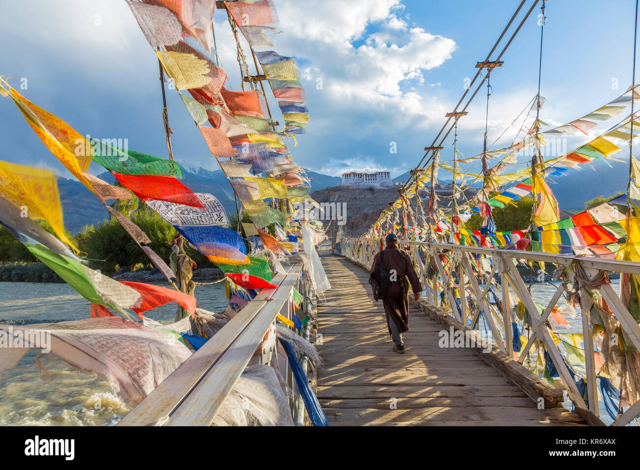 Rear view of man walking across bridge decorated with colourful prayer ...