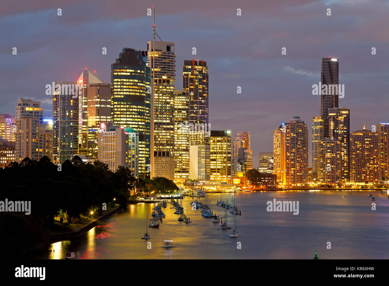 Skyline of city by the ocean at dusk, with illuminated skyscrapers ...