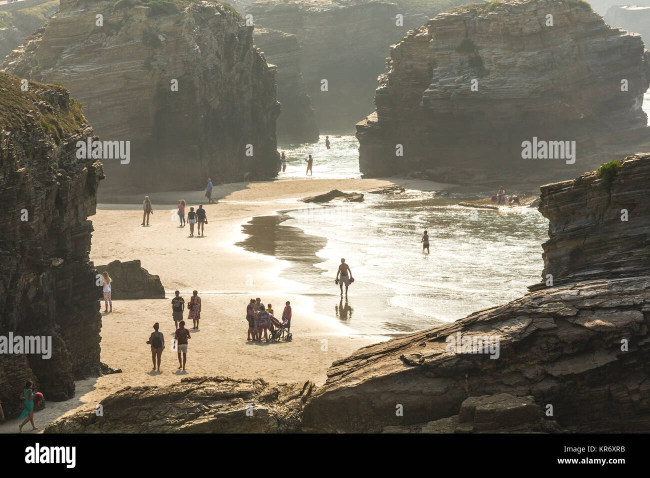 People on sandy beach surrounded by rocks Stock Photo - Alamy