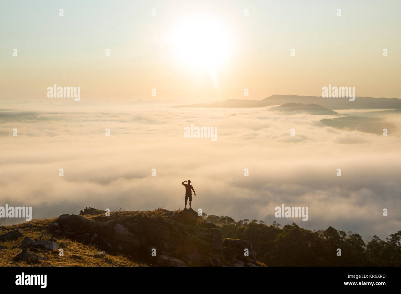 Rear view of man standing on top of mountain, admiring landscape view ...