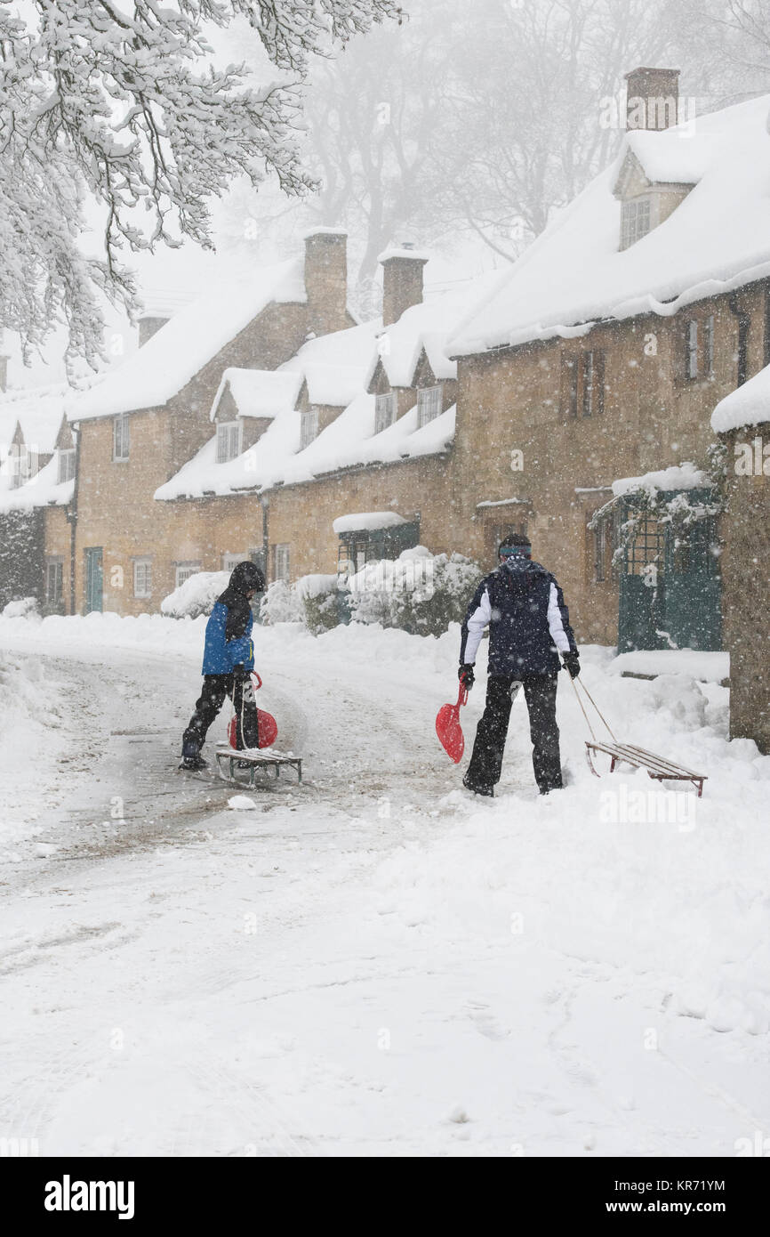 Teenage boys pulling sledges in Snowshill village in the december snow ...