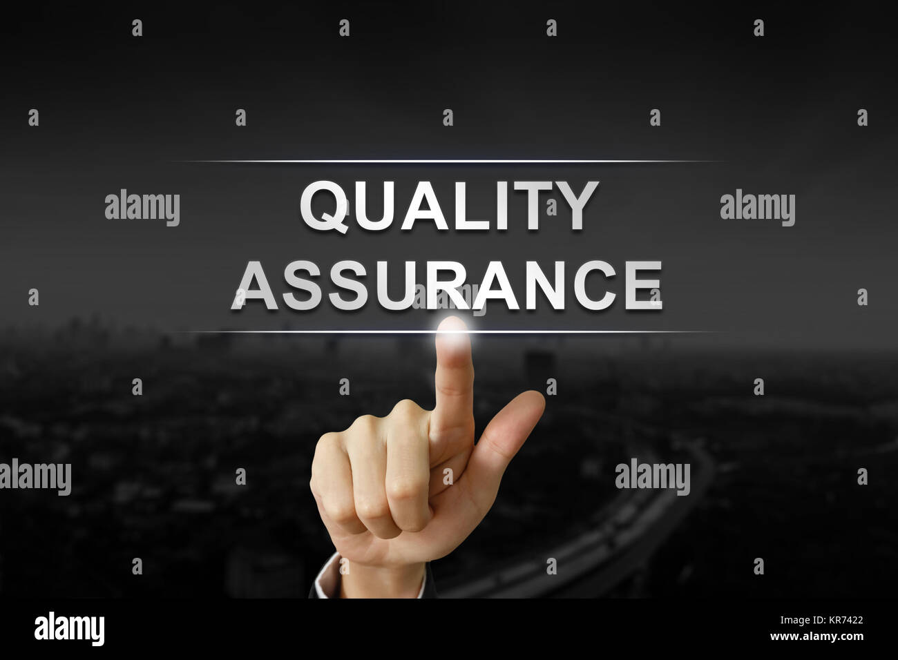 business hand pushing quality assurance button on black blurred ...