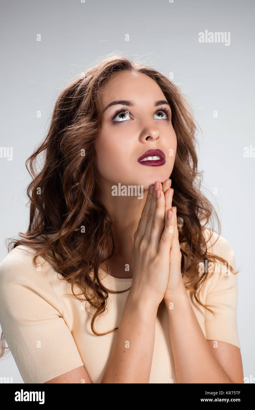 Woman is looking imploring over gray background Stock Photo - Alamy