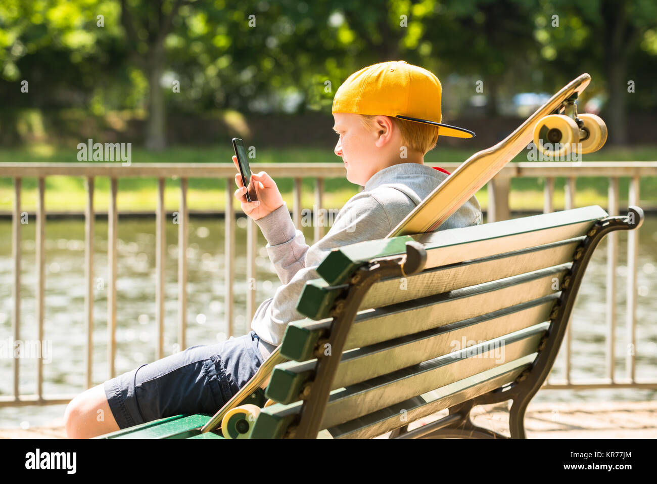 Boy Sitting On Bench Using Mobile Phone Stock Photo - Alamy