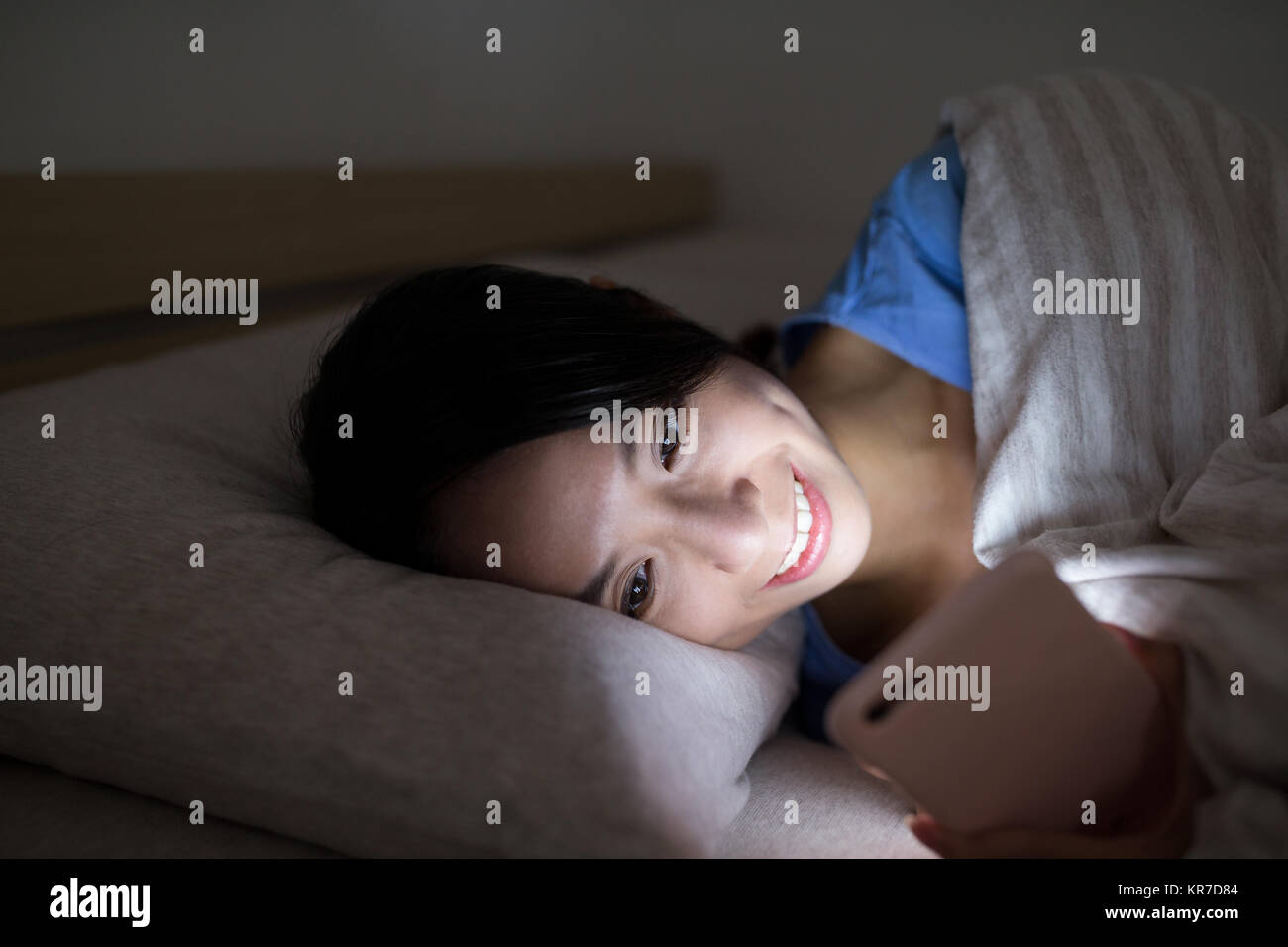 Woman using mobile phone and lying on bed Stock Photo - Alamy