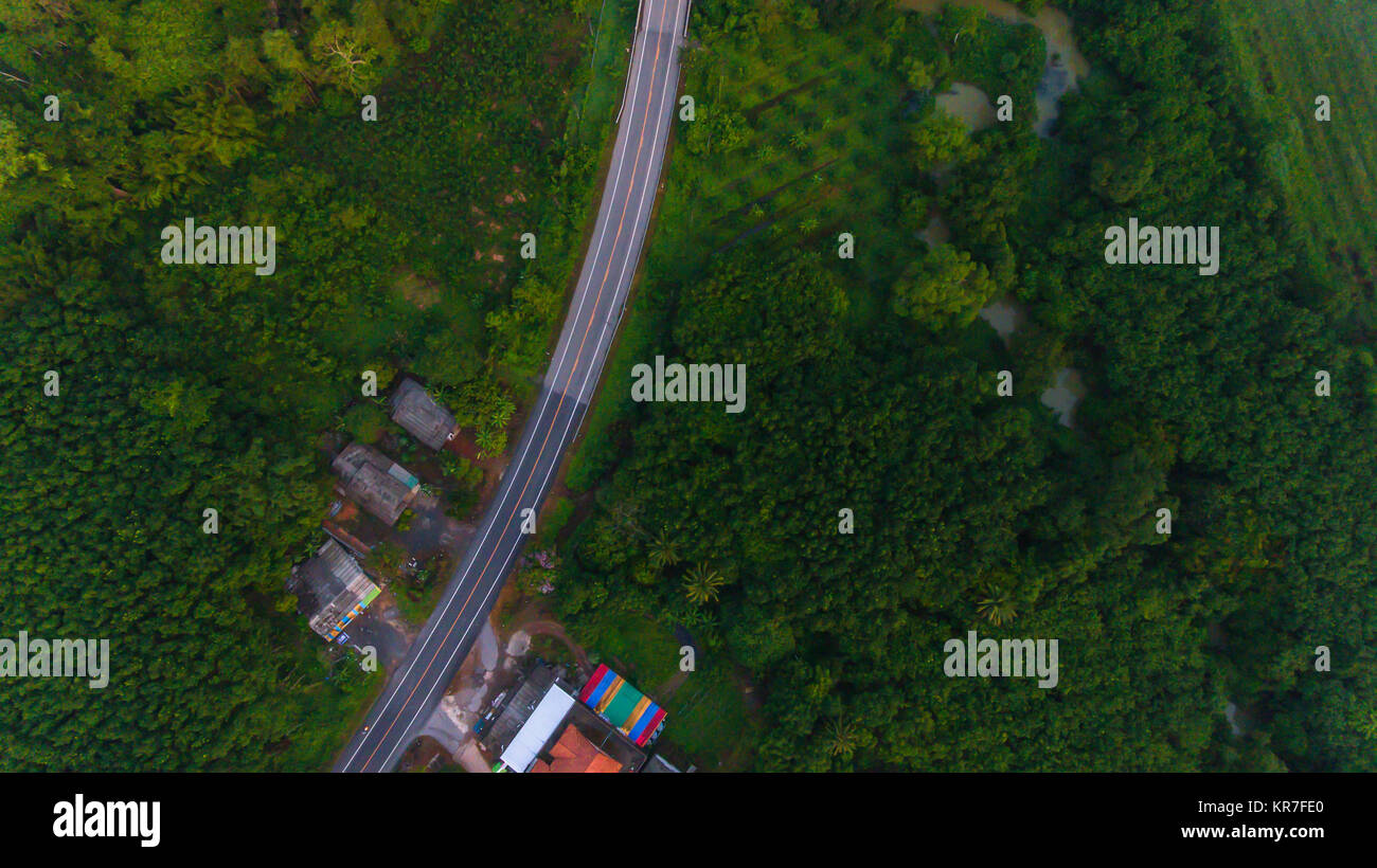 Aerial view over mountain road going through forest landscape in ...