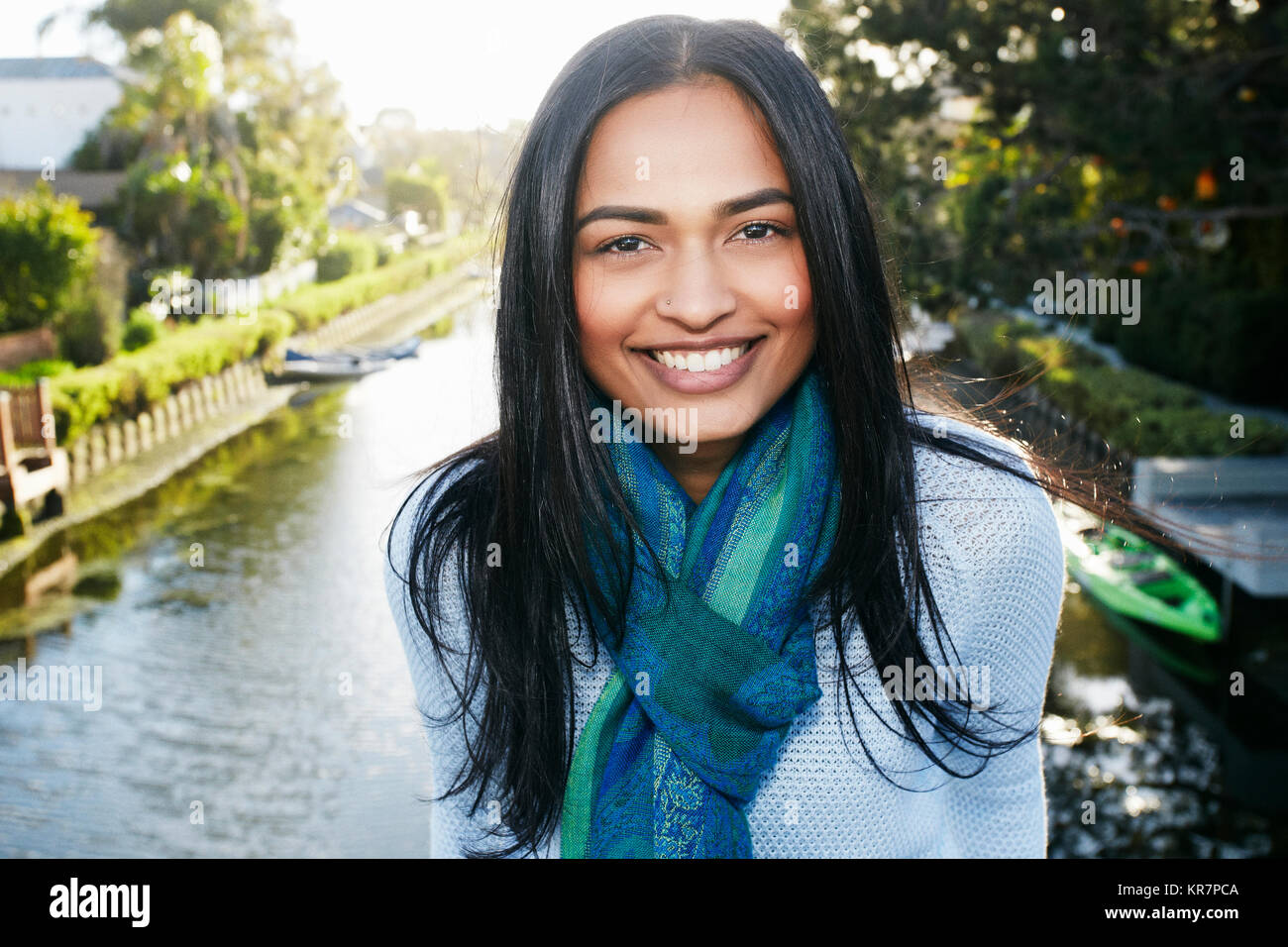 Smiling mixed race woman standing near canal Stock Photo - Alamy